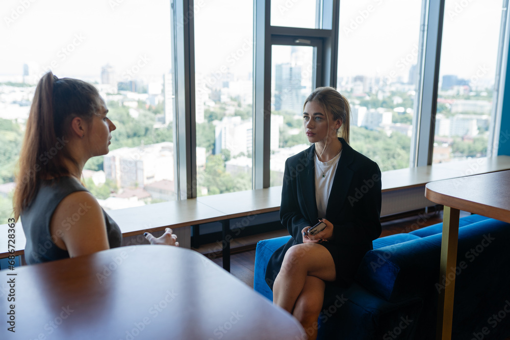 Lady with crossed legs talks to colleague during break near window ...