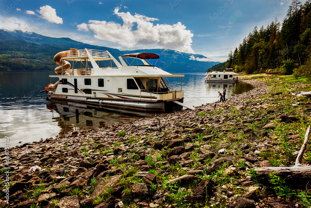 A family enjoying a houseboat vacation while parked on the shoreline of ...