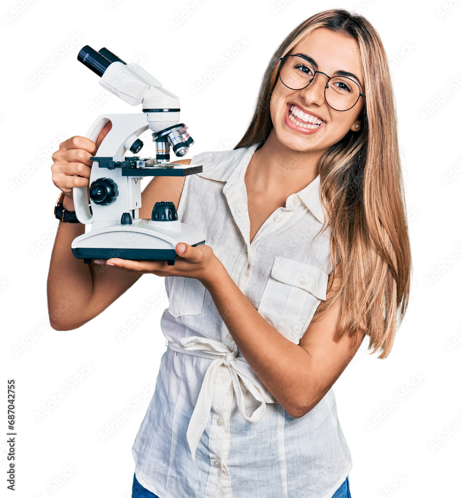 Hispanic young woman holding microscope looking positive and happy ...