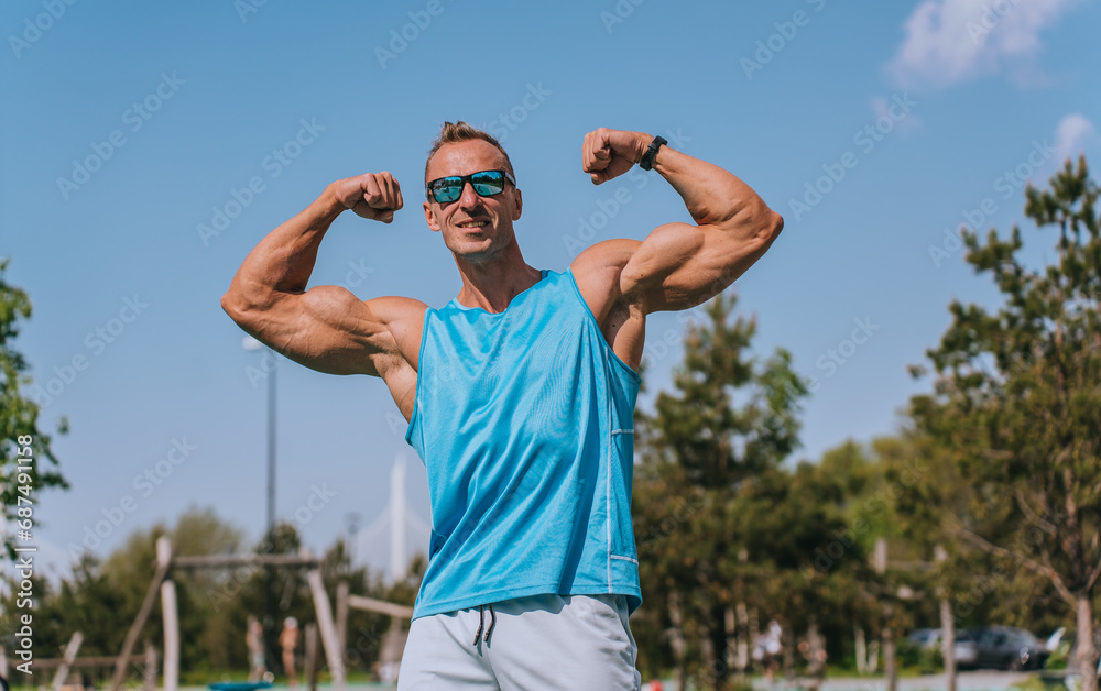 Strong caucasian bodybuilder in sunglasses and sportswear showing ...