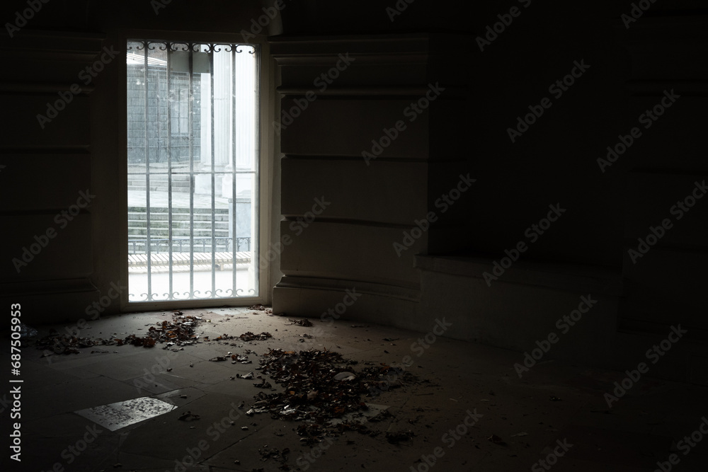 An enclosed dark room with leaves on the floor, light coming in from a ...