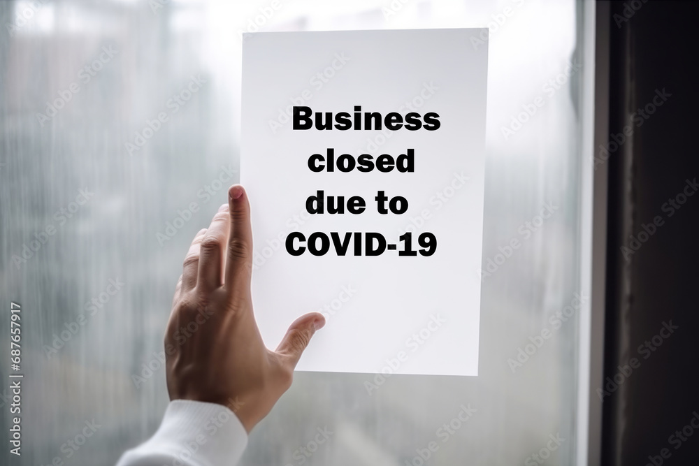 Hands posting “Business Closed Due to COVID-19” sign on glass door or ...