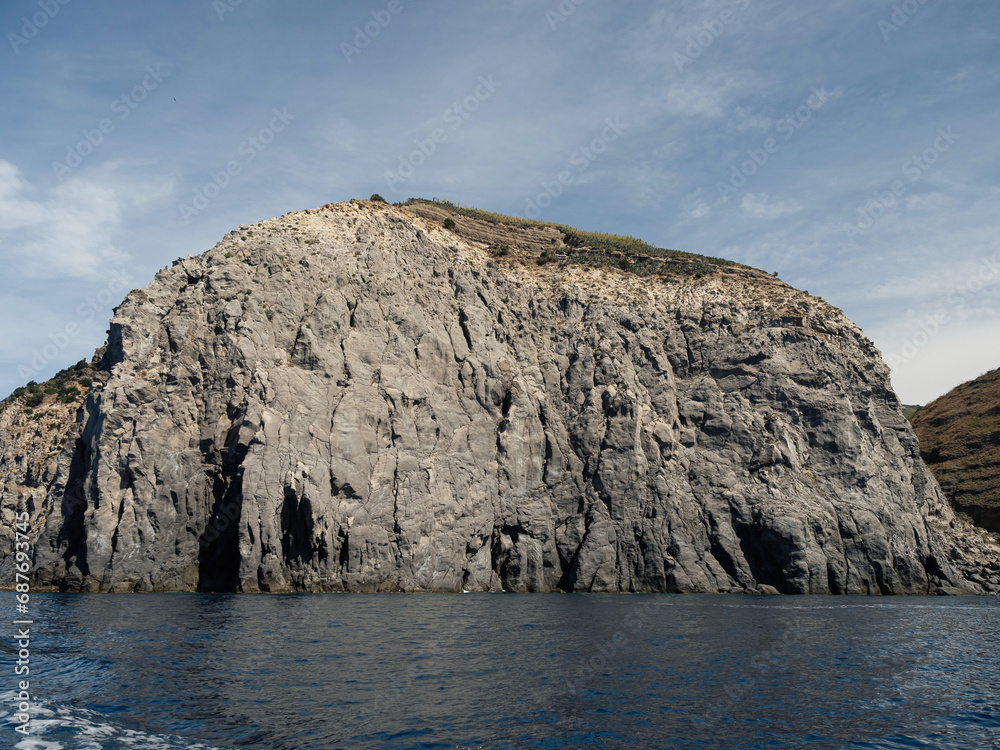 Weathered seaside rock face texture with parts of green and blue water ...
