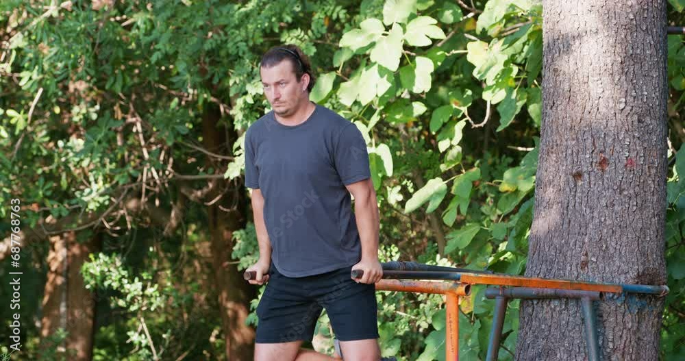 Man maintains health by doing exercises outdoors. Man pumps pectoral ...