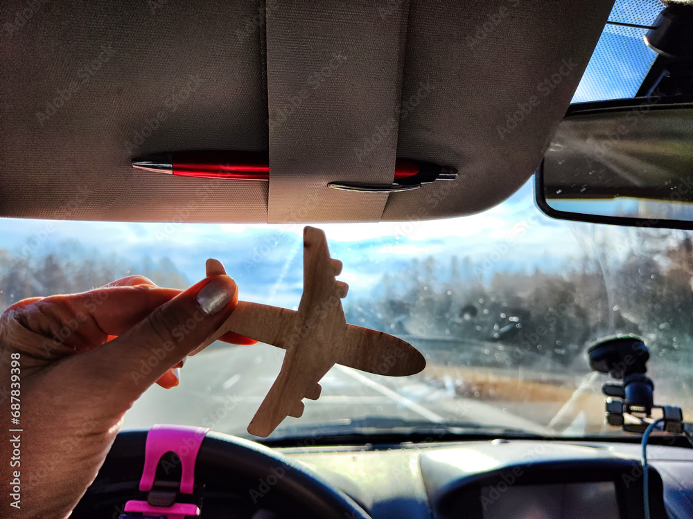 Small wooden toy airplane in the female driver's hand in a car on the ...