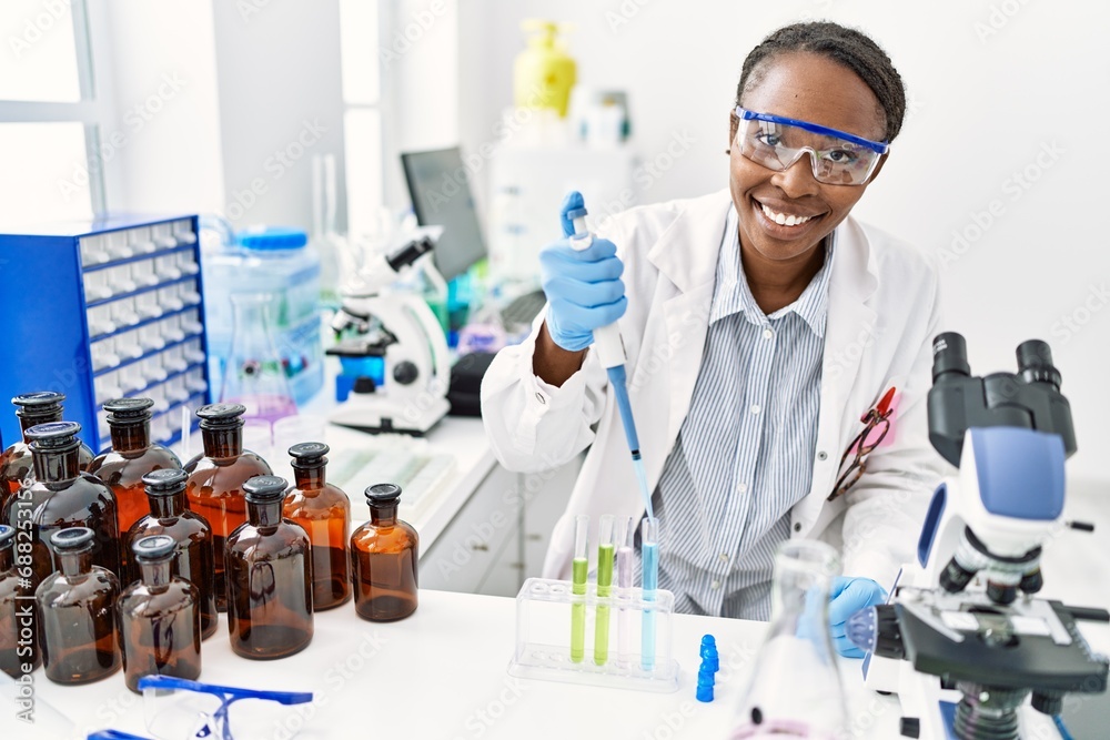 African american woman scientist pouring liquid on test tube at ...