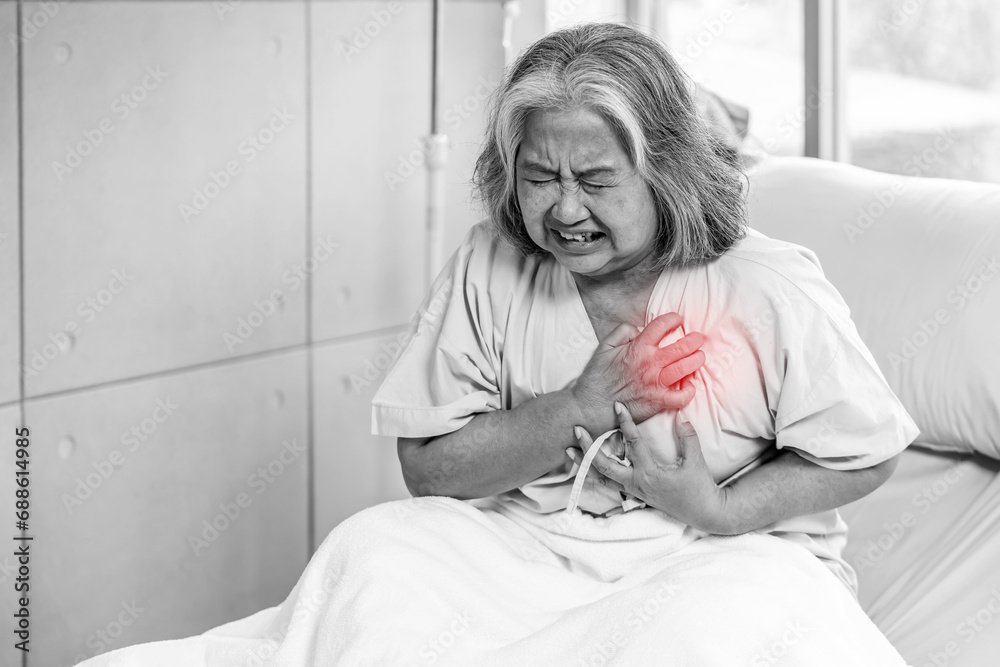 Asian senior old woman sitting on bed suffering from sudden heart ...