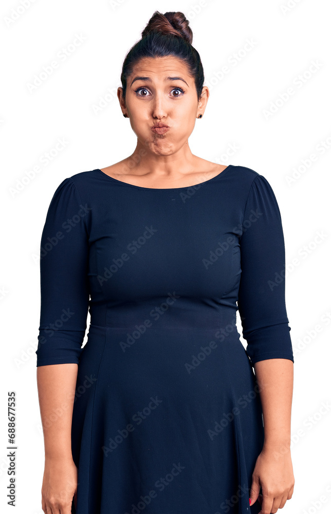 Young beautiful brunette woman wearing casual dress puffing cheeks with ...
