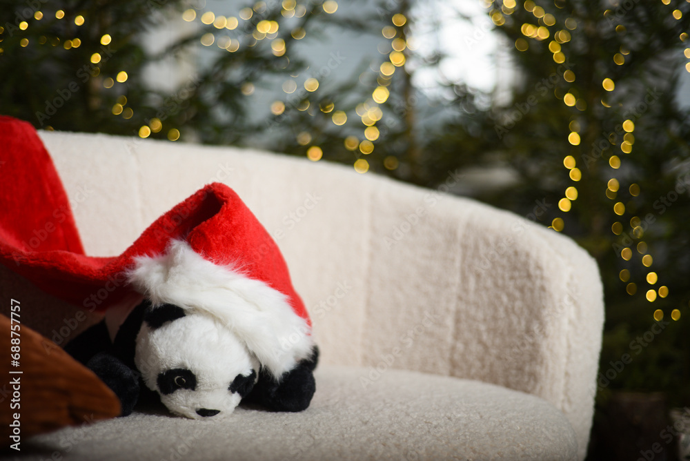 toy panda with a red gnome's Christmas hat is sitting on a white sofa ...
