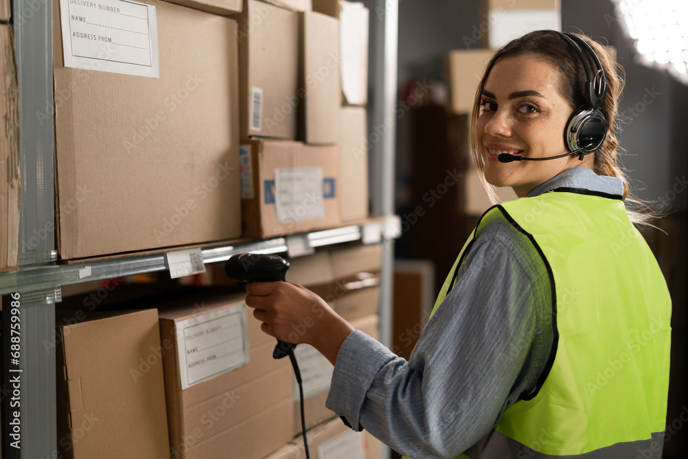 Portrait of a smiling warehouse staff using a headset while working in ...