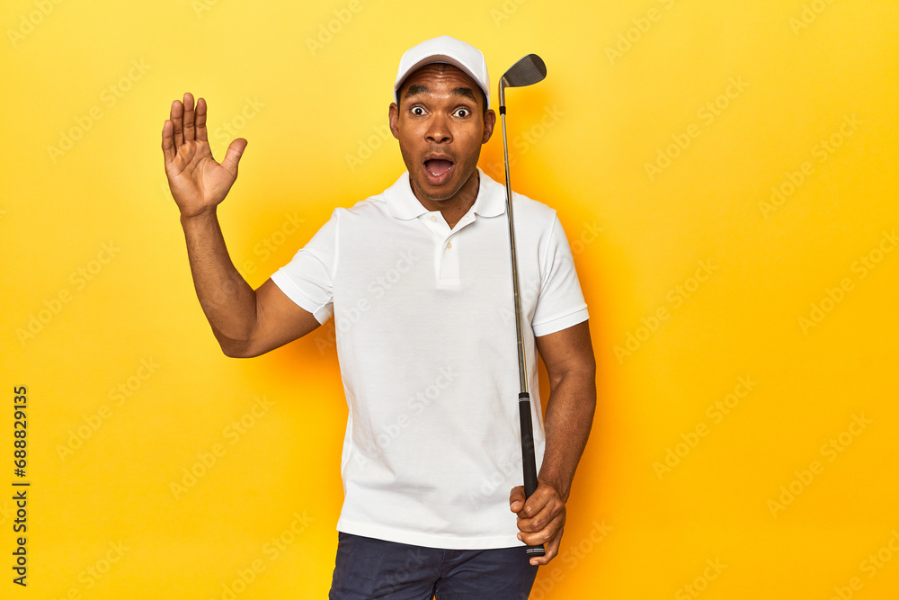 African American man golfer, yellow studio backdrop, receiving a ...