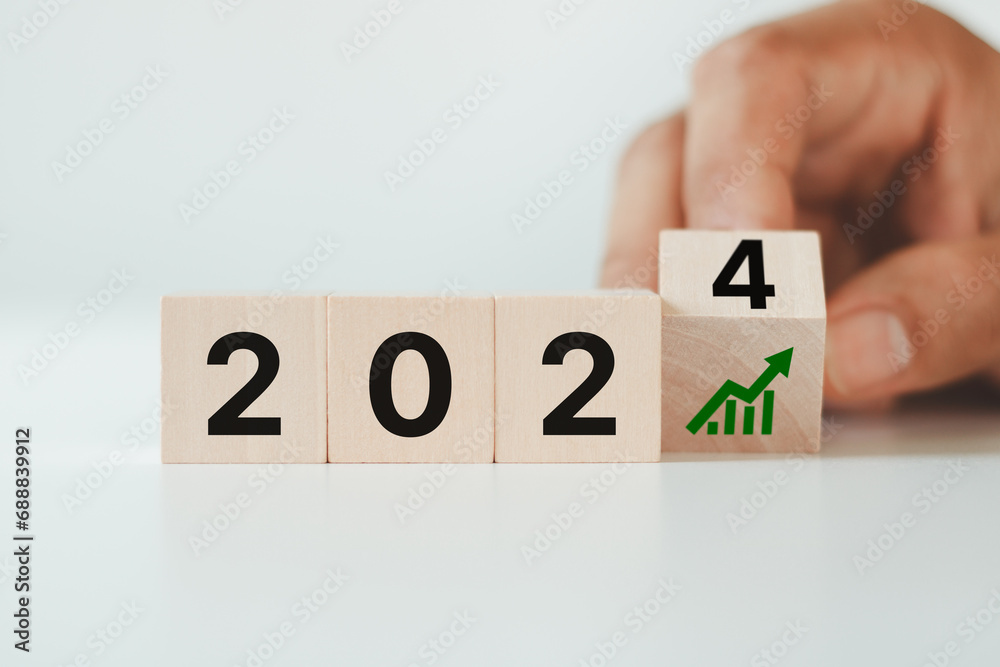 Hand flipping wooden cube block inscribed 2024 and growth icon on smart ...