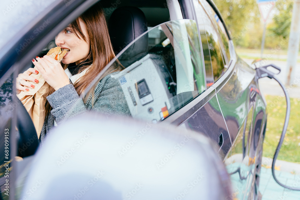 Lunch time. Hungry charming lady eating at her car while waiting ...