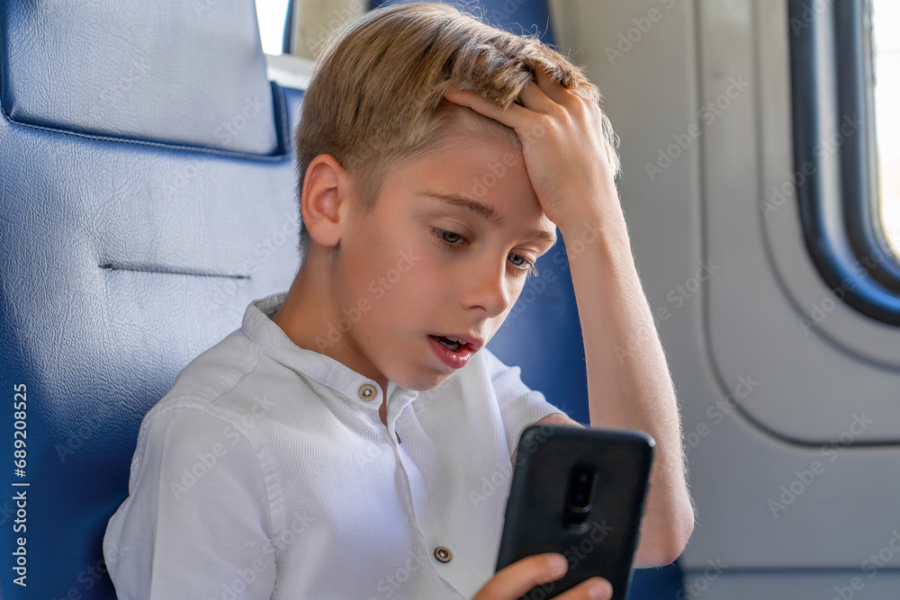 Astonished by what he sees on his phone screen, a caucasian teenage boy ...