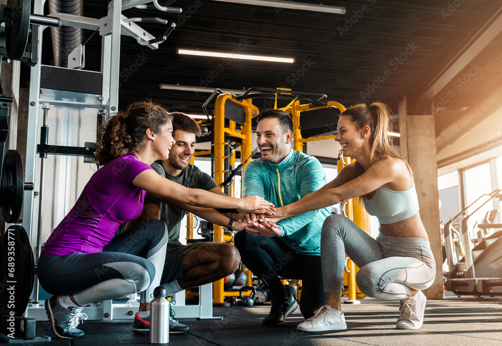 Happy athletes joining hands in unity in a gym. Group of good looking ...