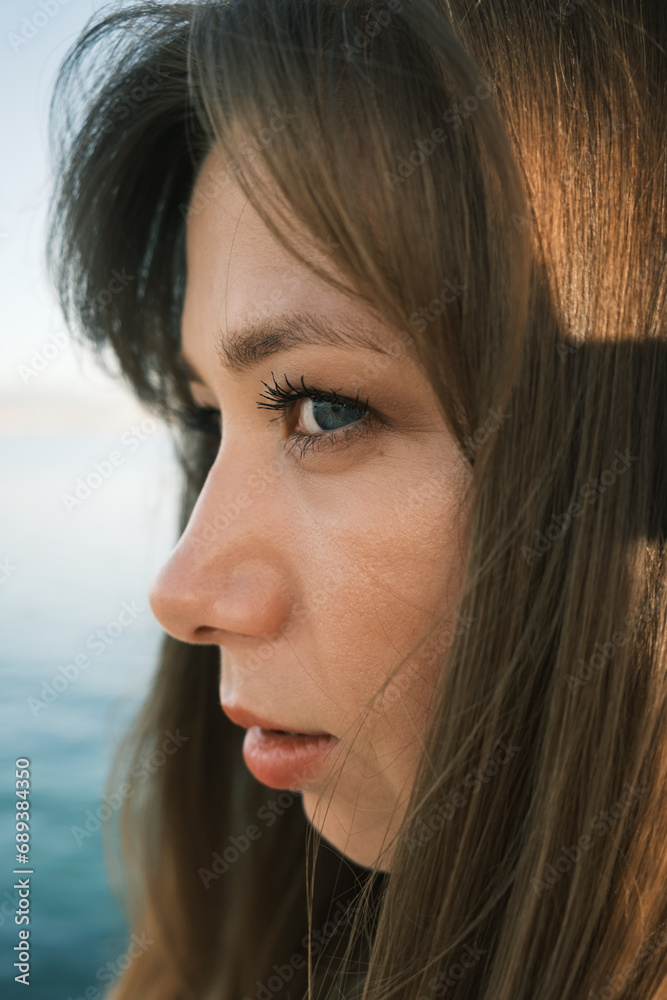 Side profile of a contemplative woman by the sea, with a thoughtful ...