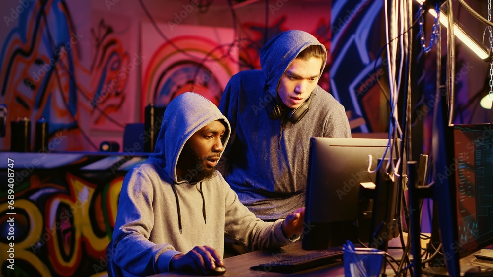 New member in hacking group receiving guidance from knowledgeable rogue programmer acting as his ...