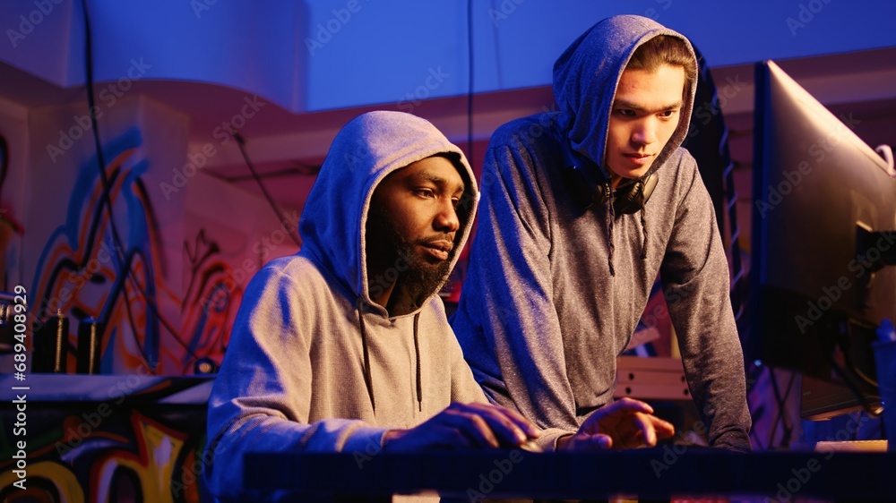 African american hacker talking to asian colleague in rundown hiding ...