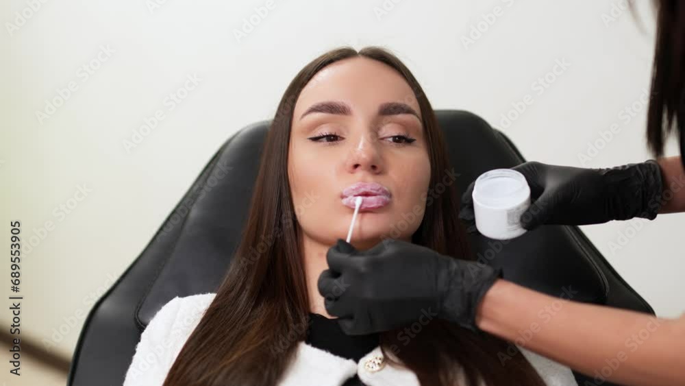 The cosmetologist applies anesthesia and pain relief to the patient’s ...