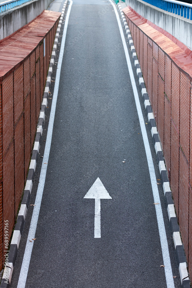 Top-down view of a directional arrow on street between walls, guiding ...
