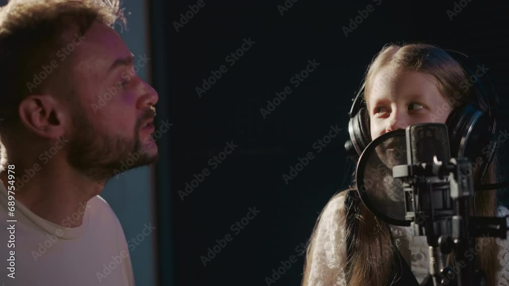 Kid with teacher sing in audio recording studio. Happy little girl ...