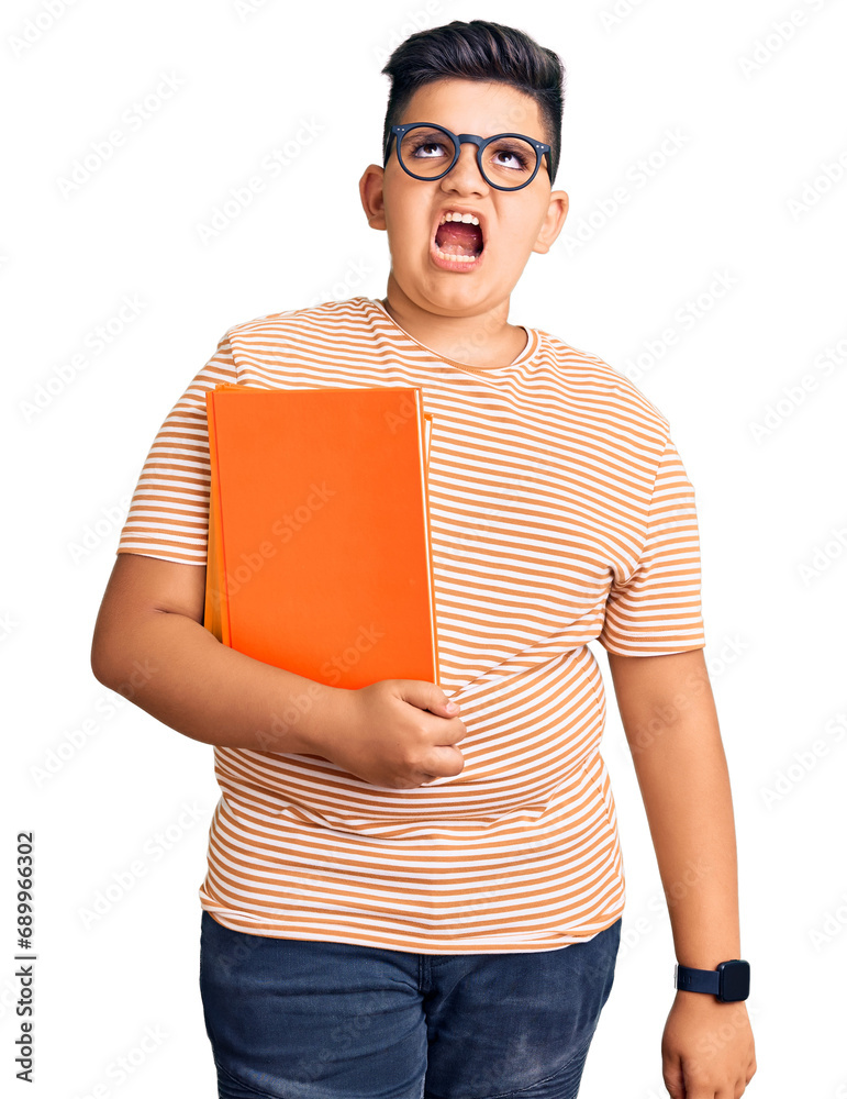 Little boy kid holding book wearing glasses angry and mad screaming ...