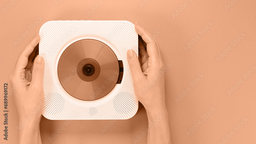 Hands holding stylish white compact CD player. Image toned in Peach ...