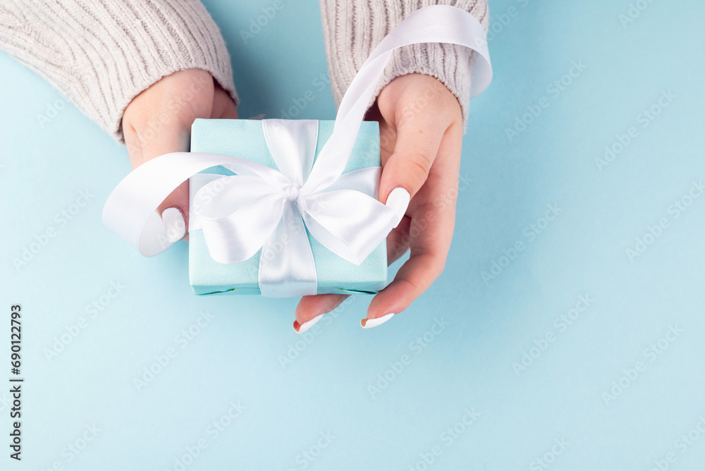 First person top view photo of female hands holding blue gift box with ...