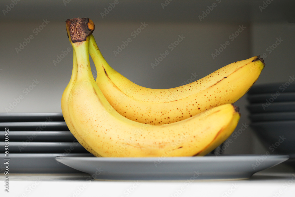 Bananas in kitchen cabinet. Blue ceramic food plates stacked. Milk soup ...