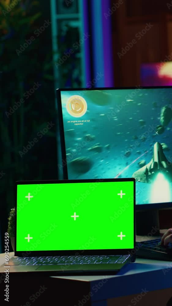Vertical video Green screen laptop next to man using gaming keyboard to ...