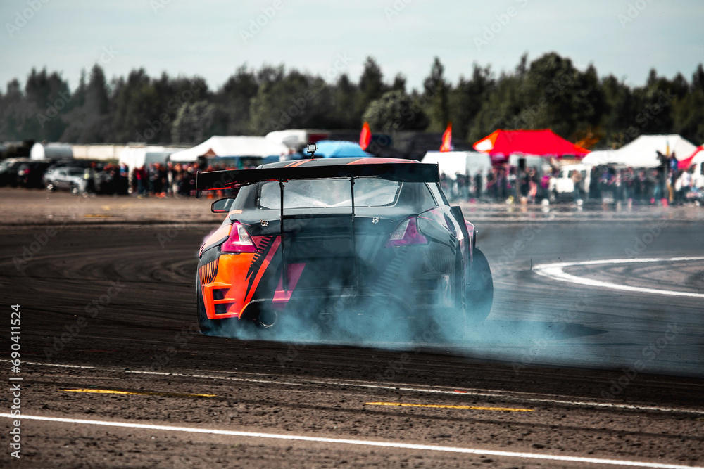 rear view of a drift car in a skid on a corner of a sports car track ...