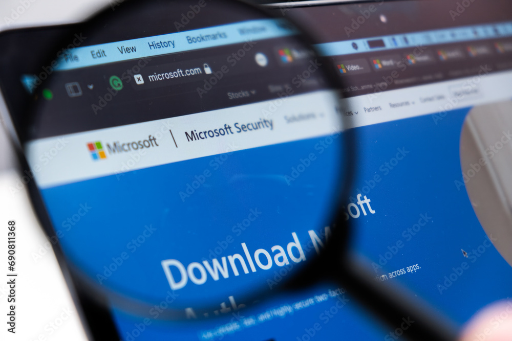 Microsoft Security logo enlarged through a magnifying glass on a laptop ...