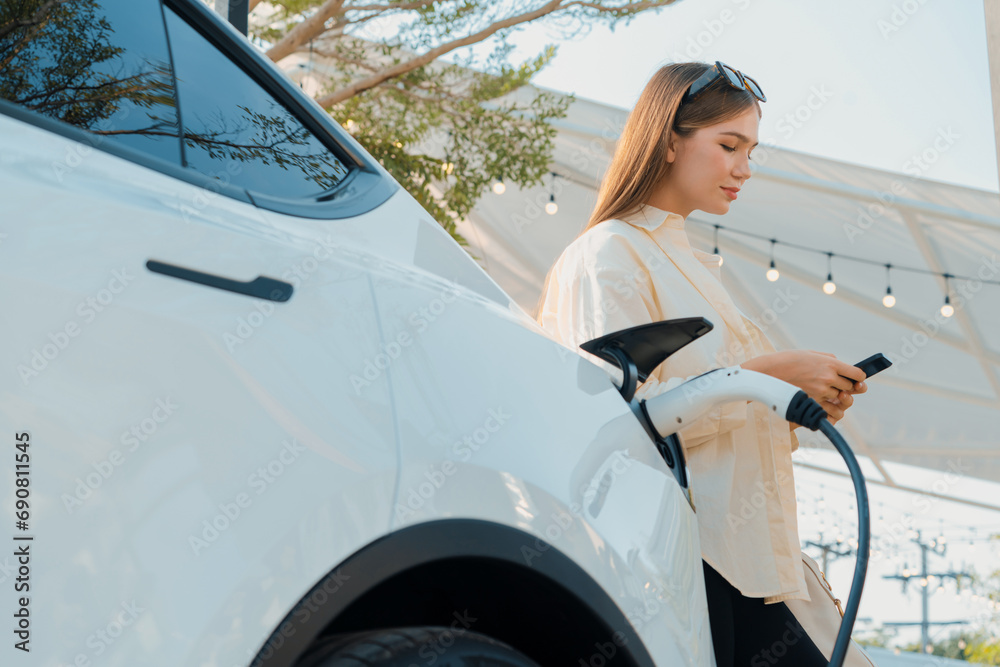Sustainable urban commute with young woman pay electricity for EV ...