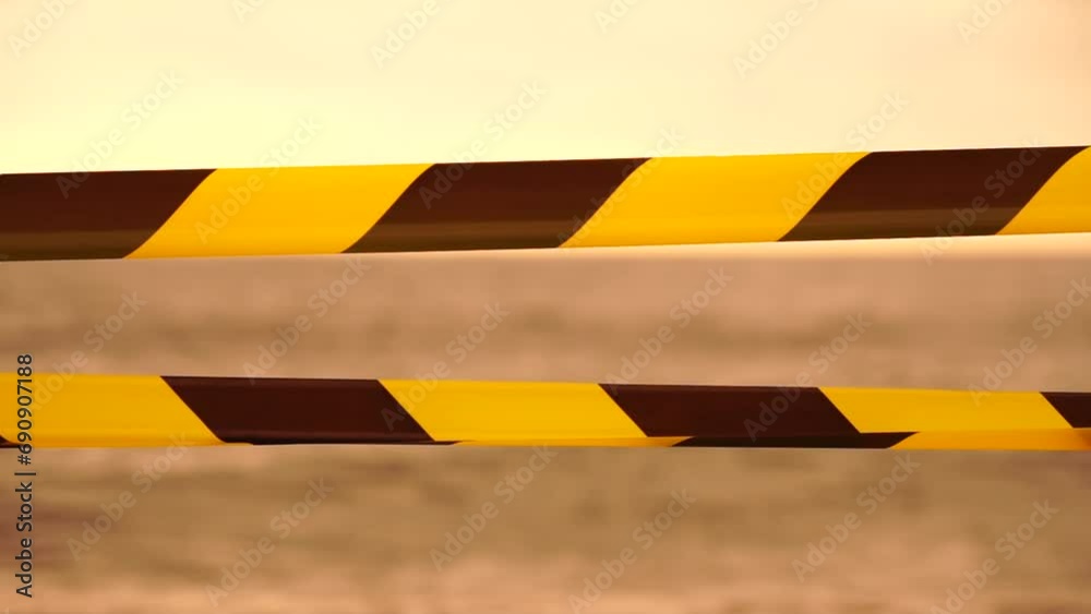 Yellow black warning tape barrier ribbon swinging in the wind across ...