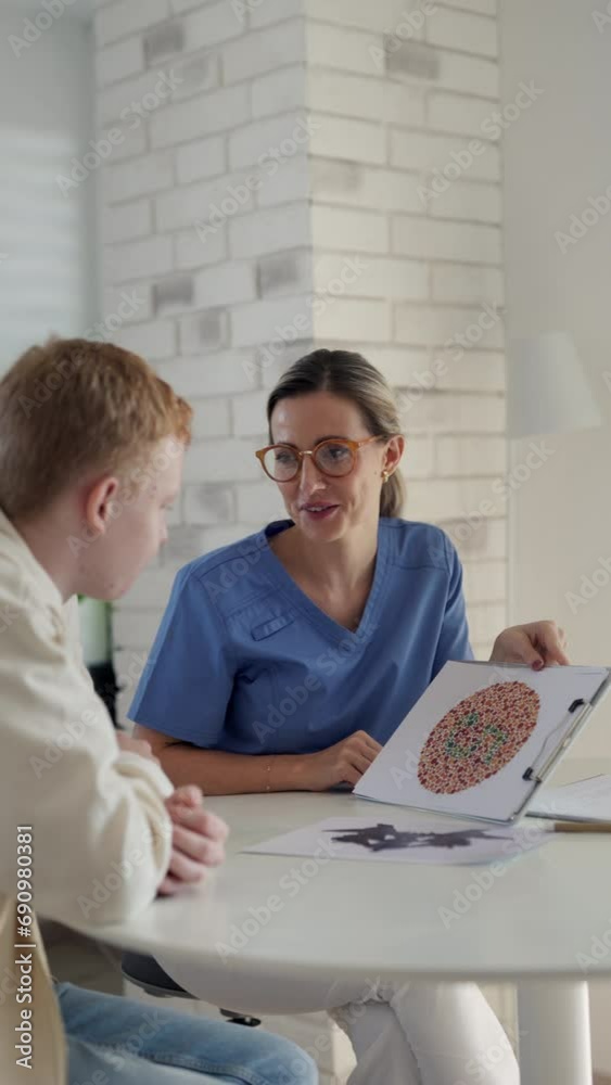 Ophthalmologist examining teenage boys's vision, doing Ishihara colour ...