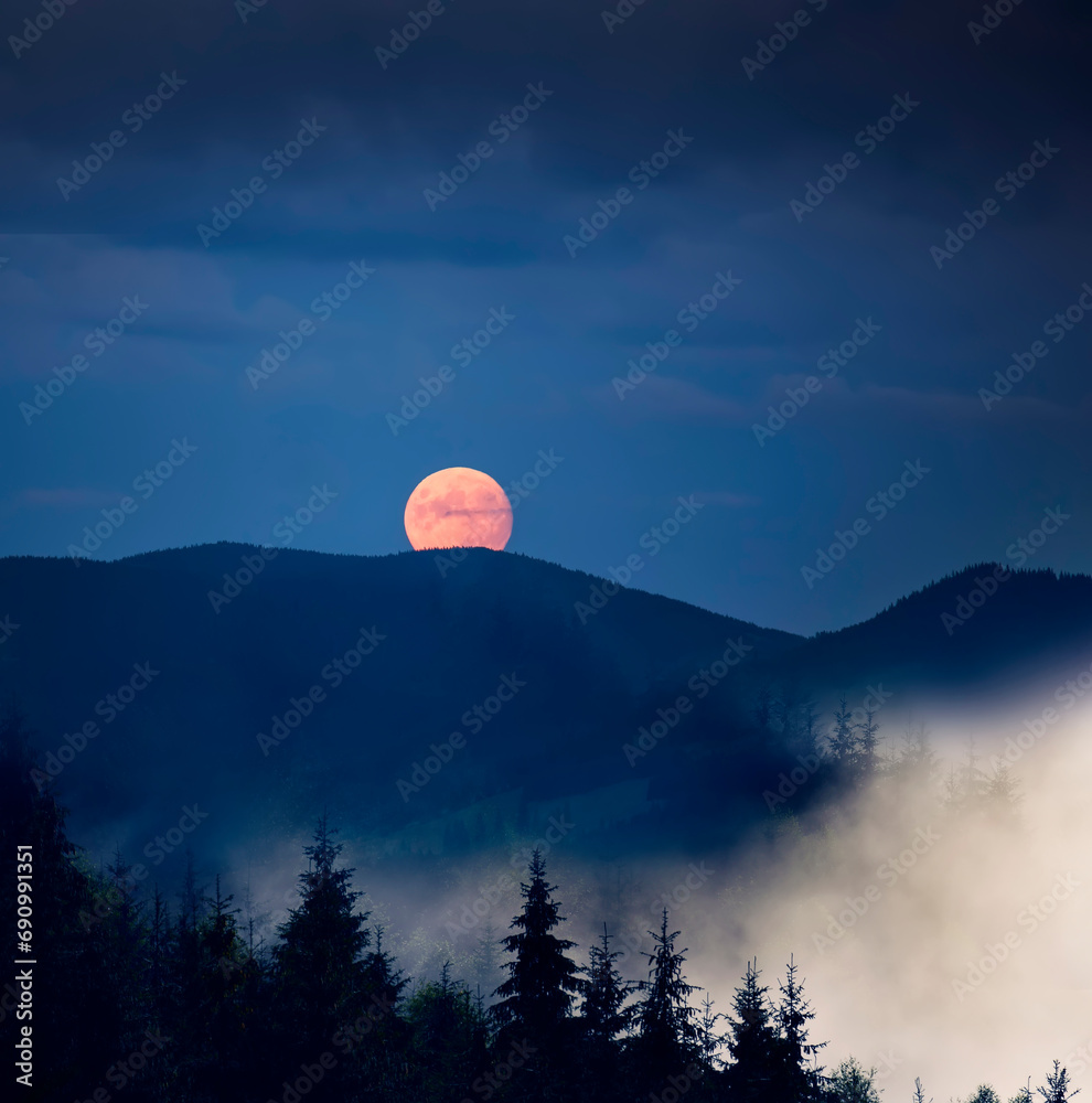 Night dramatic stage view. Silhouettes of mountain peaks and fir trees ...