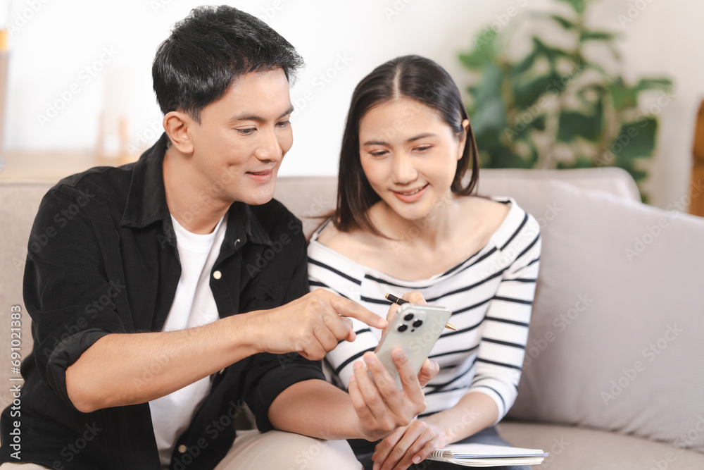 young Asian couple engaged in online shopping, wife woman holds notepad ...