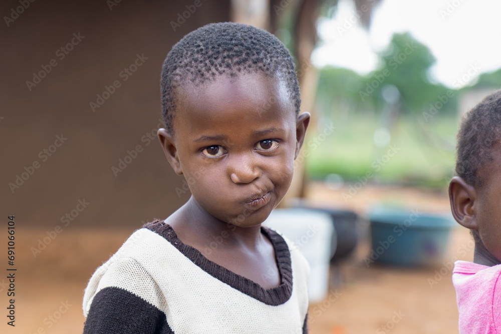village african child, standing in the yard , playing pulling faces ...