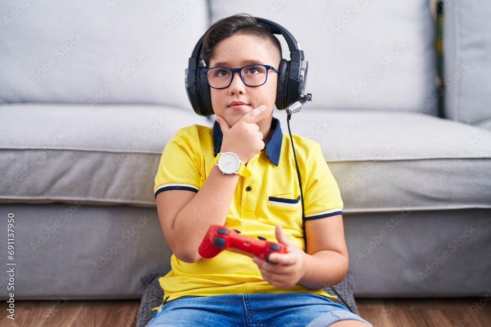 Young hispanic kid playing video game holding controller wearing ...