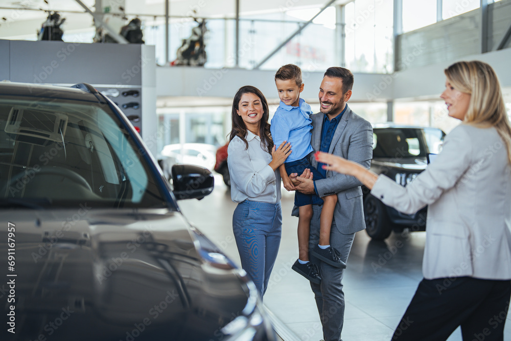 Family in a car dealership. Happy family came to an agreement with a ...