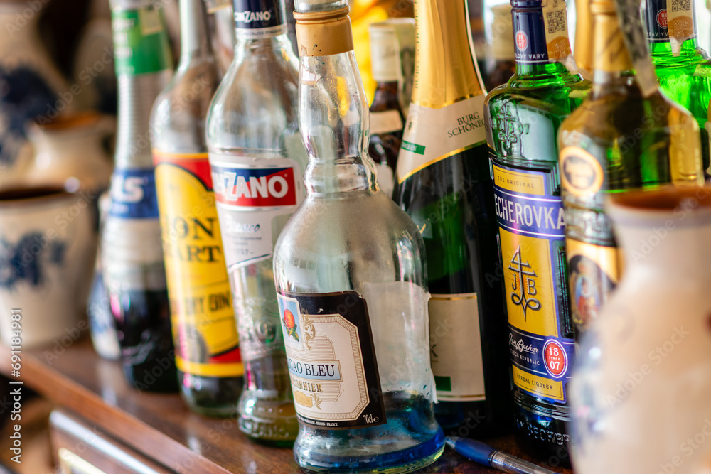 Alcohol bottles placed next to each other in a row at a bar. Glasses ...