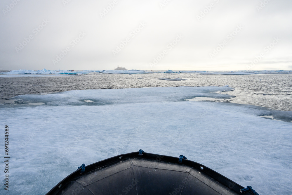 Bow of a ridged hull inflatable boat motoring though floating sea ice ...