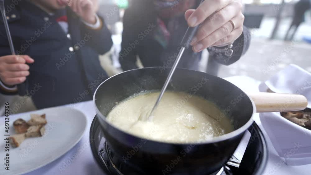 Traditional Swiss food, closeup hand holding fork with bread dipping in ...