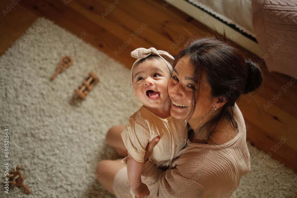 Laughter fills the room as a mother lifts her delighted baby, a moment ...