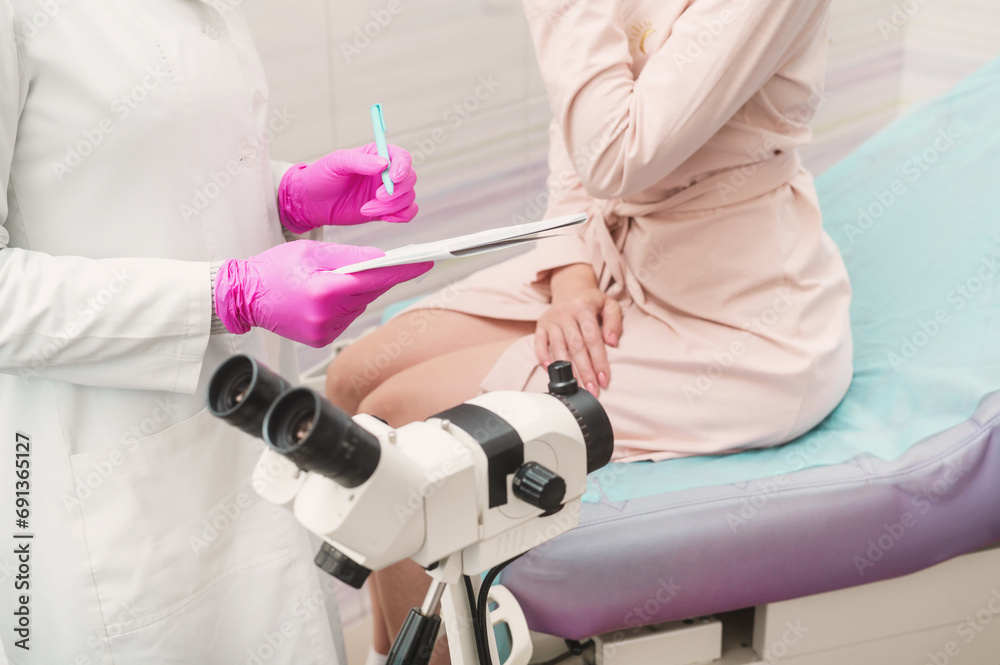 A young woman in a hospital gown at a gynecologist's appointment. A ...