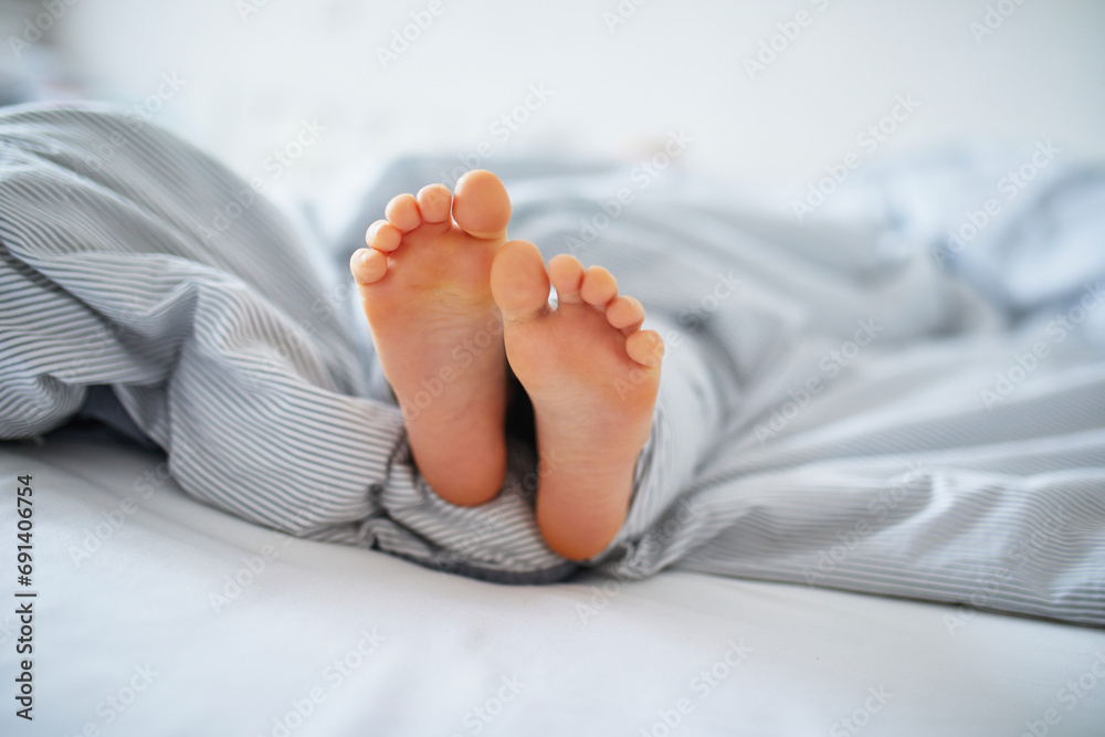 Little child's feet in bed covered with blanket Stock Photo | Adobe Stock