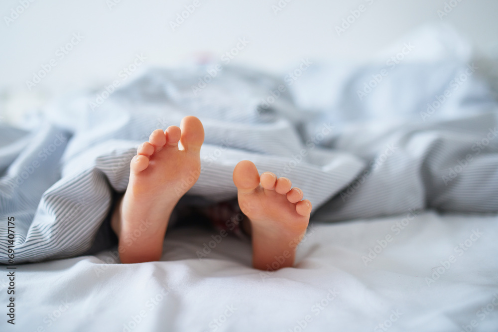 Little child's feet in bed covered with blanket Stock Photo | Adobe Stock