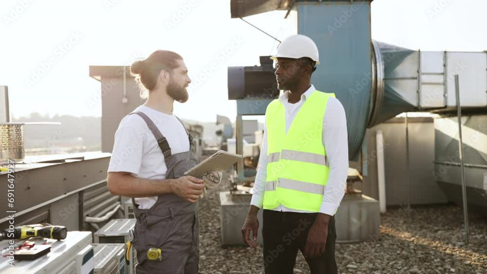 Serious engineers standing and shaking hands while working together on ...