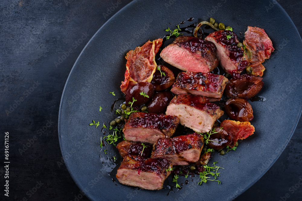 Traditional fried wild hare back filet with plums, cranberries and ...