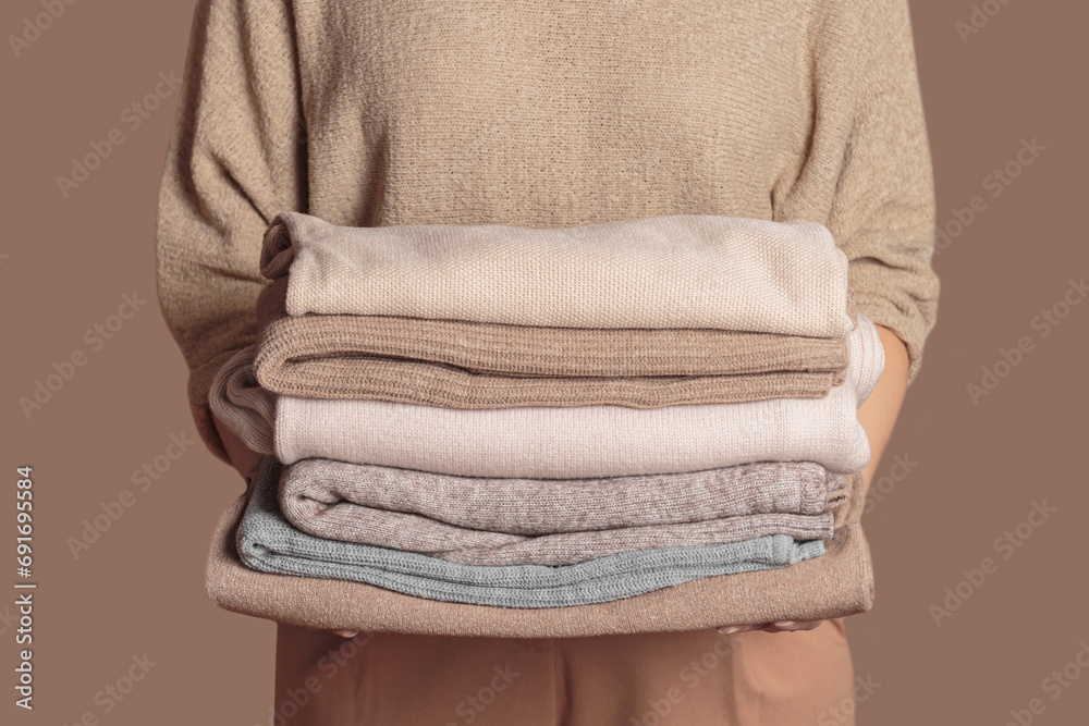 Woman holding stack of clothes with used wardrobe, ready to give away ...